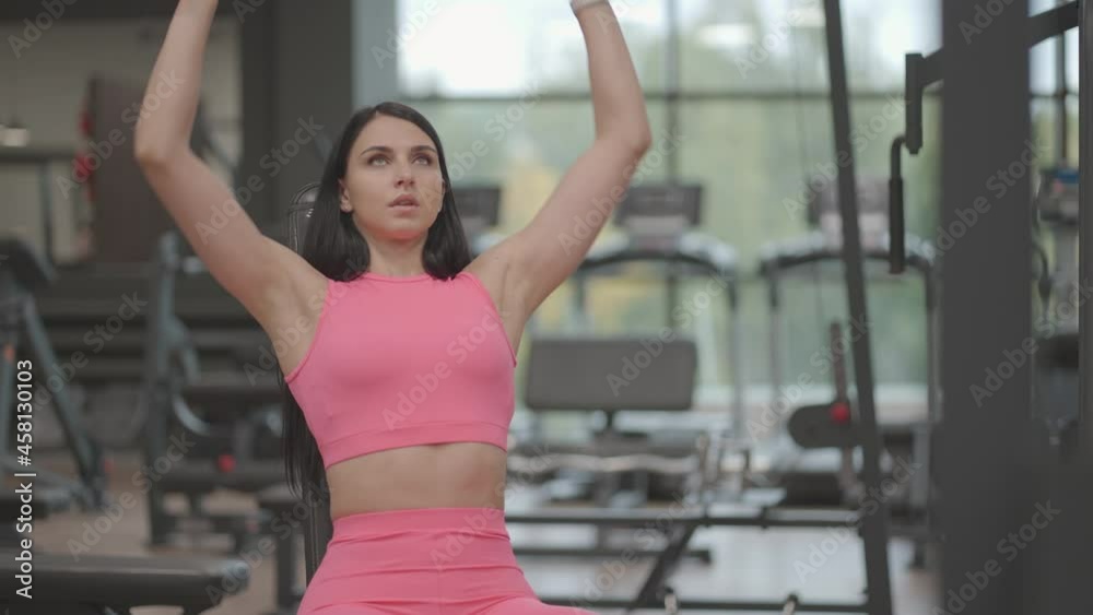 Hispanic young woman doing overhead presses with dumbbells. Cheerful ...