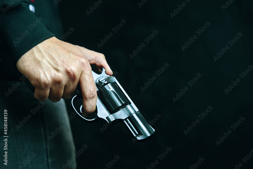 Firearm in man's hand. Criminal with revolver on dark background ...
