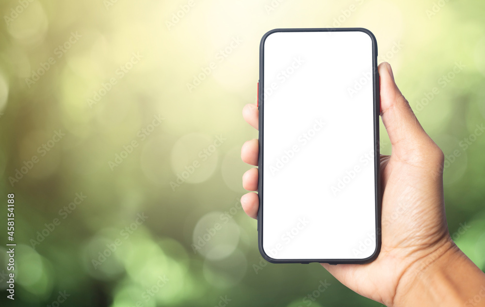 hand holding black smartphone with white screen mockup and sun light ...