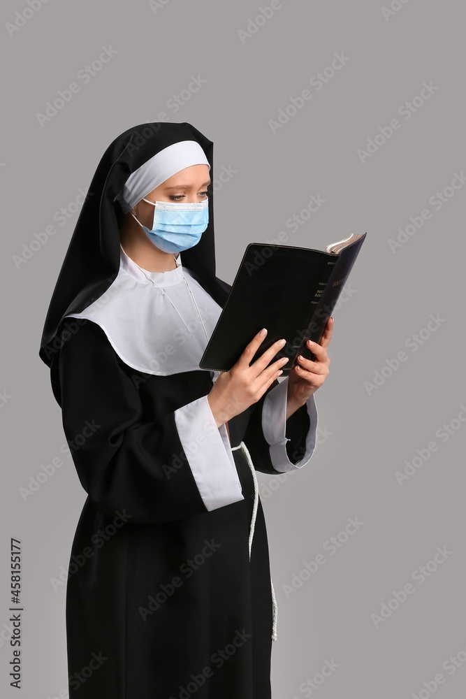 Young nun in medical mask and with Bible on grey background Stock Photo ...