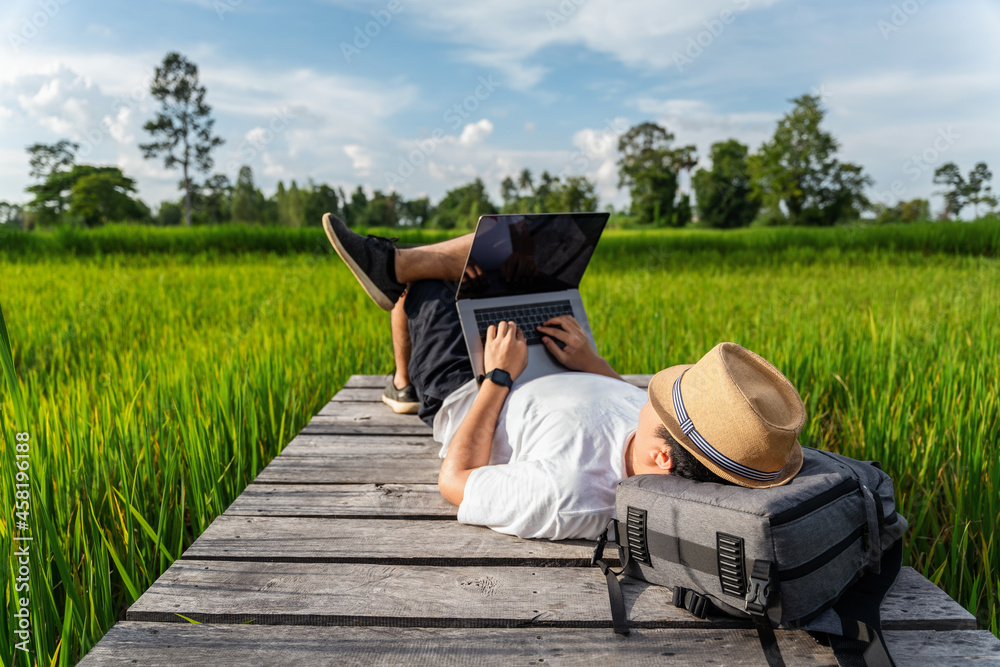 Asain young man working, using laptop computer in nature. Freelance ...