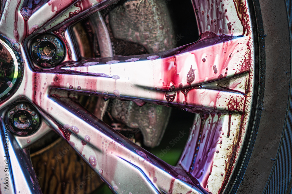 Car wheel cleaning process. Rim cleaner gives purple chemical reaction ...