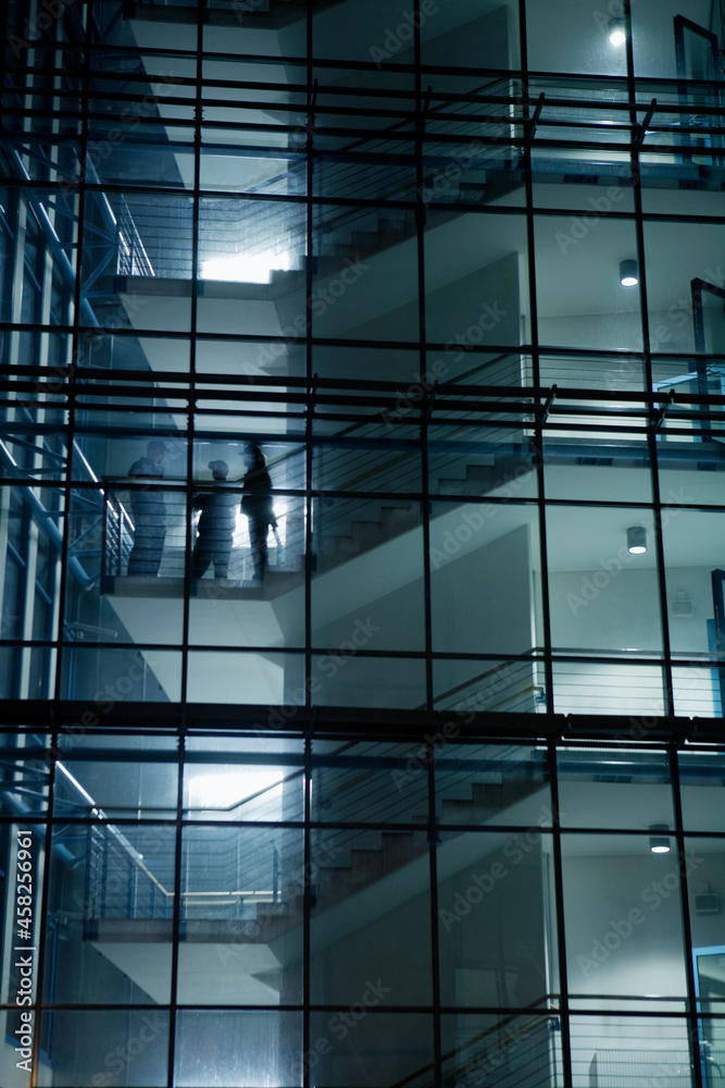 Silhouettes of security guards seen through office building windows at ...