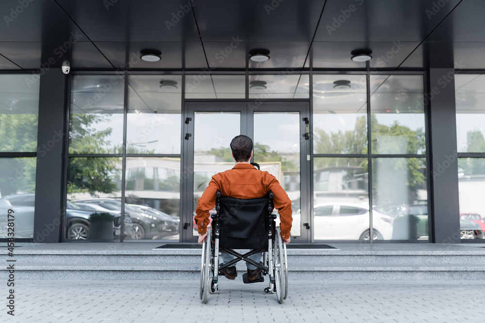 back view of handicapped man in wheelchair near stairs in front of ...