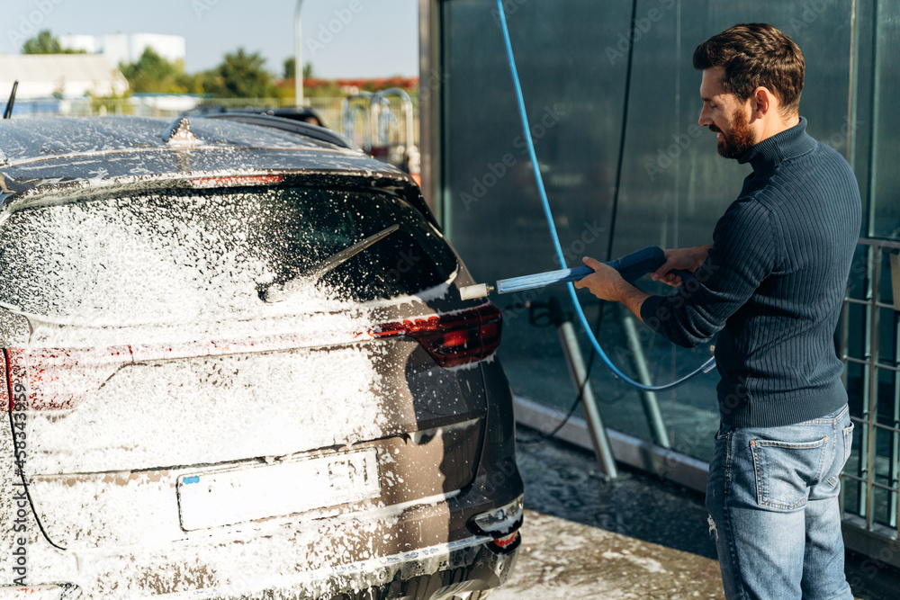Car washing by her caucasian owner. Back view of the man cleaning his ...