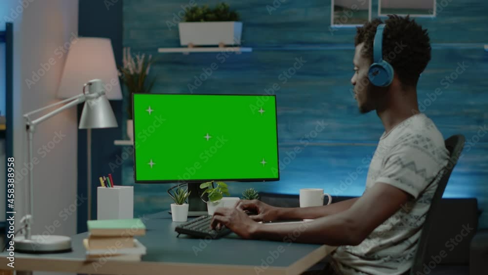 Man looking at horizontal green screen on computer for remote work ...