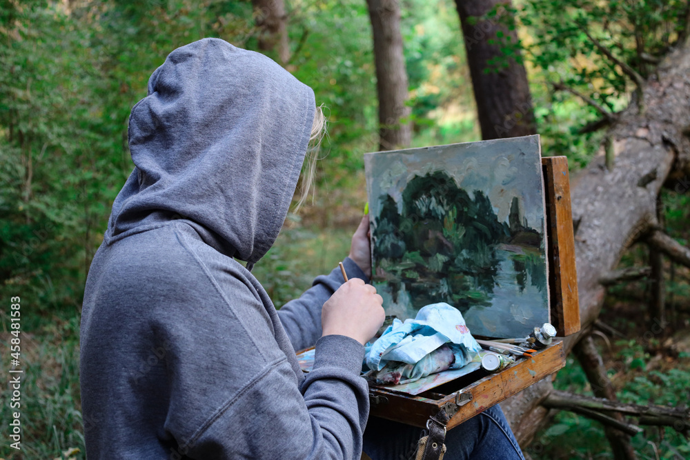 Girl draws on nature. The artist draws on plein air. Forest landscape ...