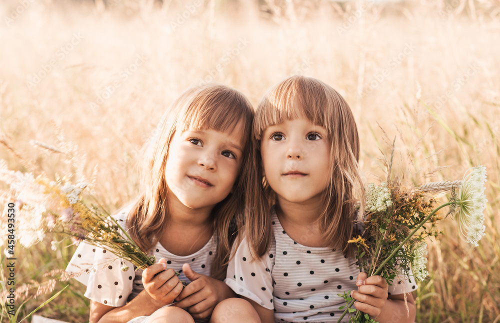 Two little happy identical twin girls playing together in nature in ...
