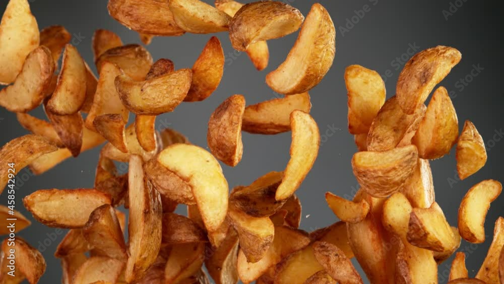 Super slow motion of flying fried american potatoes on black background ...