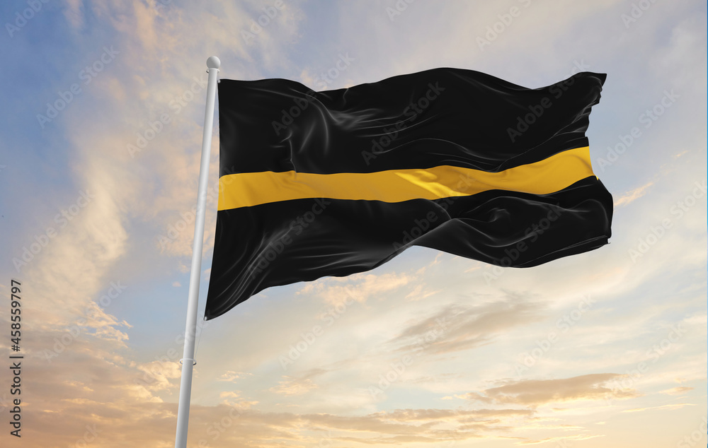 Thin Gold Line flag waving at cloudy sky background on sunset ...