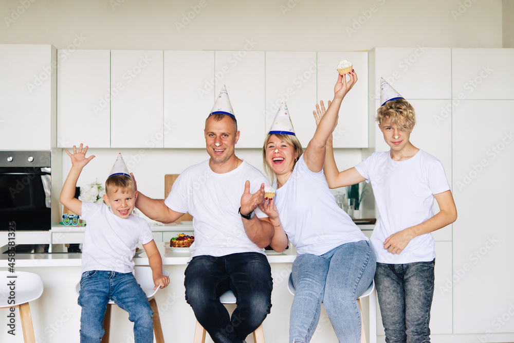 Cheerful family at home. Mom, dad and two sons. They eat pastries ...