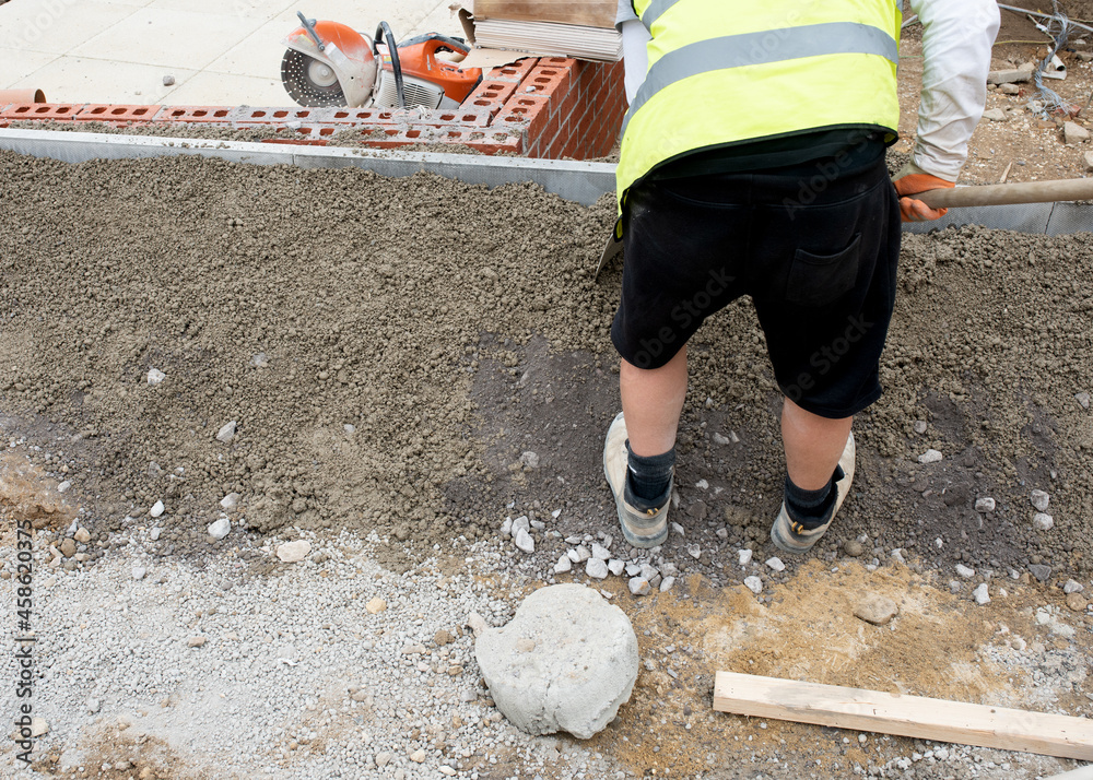 Groundworker placing edging pin kerb on semi-dry concrete during ...