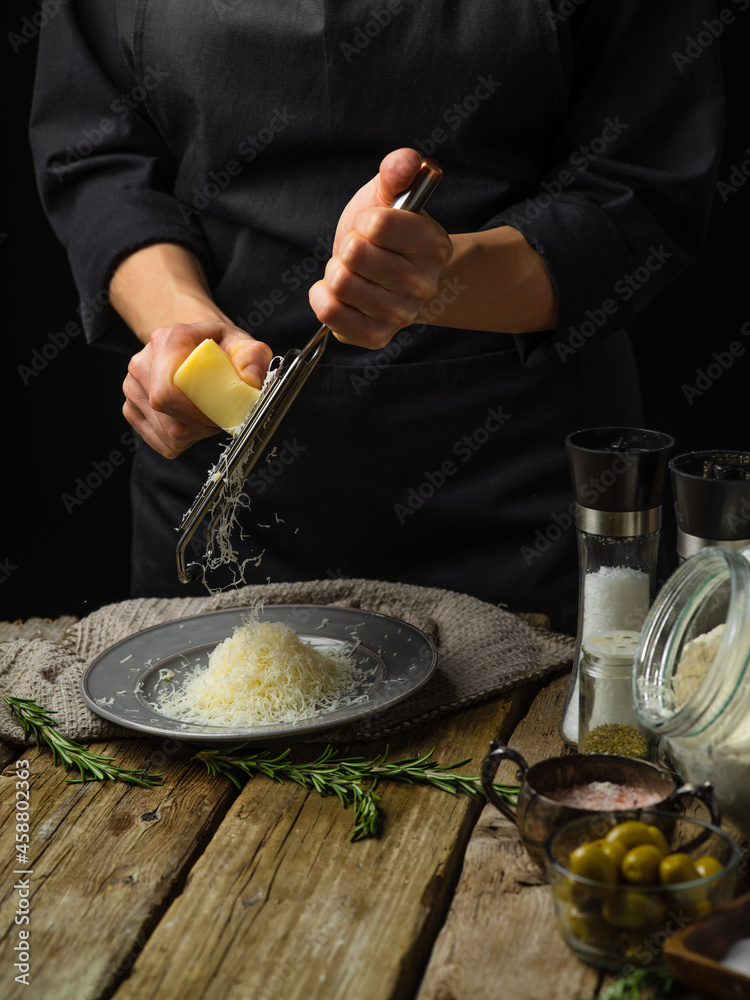 The chef is rubbing cheese on a brush. Ingredients. Black background ...