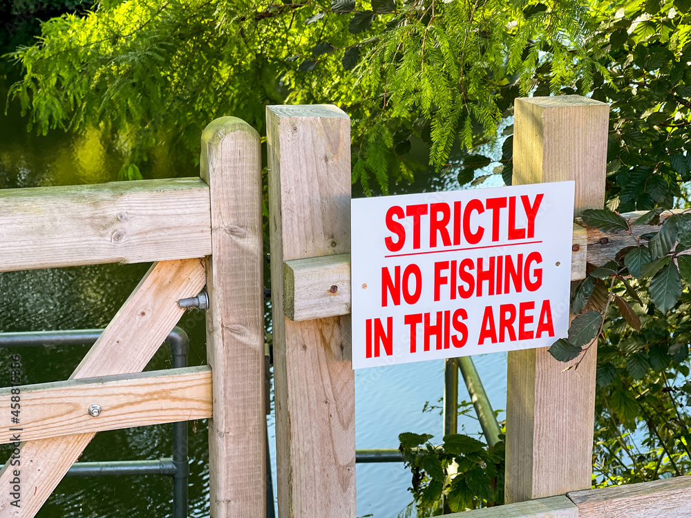 No fishing sign fixed to a wooden post at the entrance to a pool in a ...