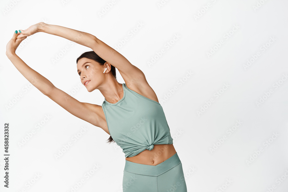 Young female athlete doing arm stretches, warm-up before yoga class ...
