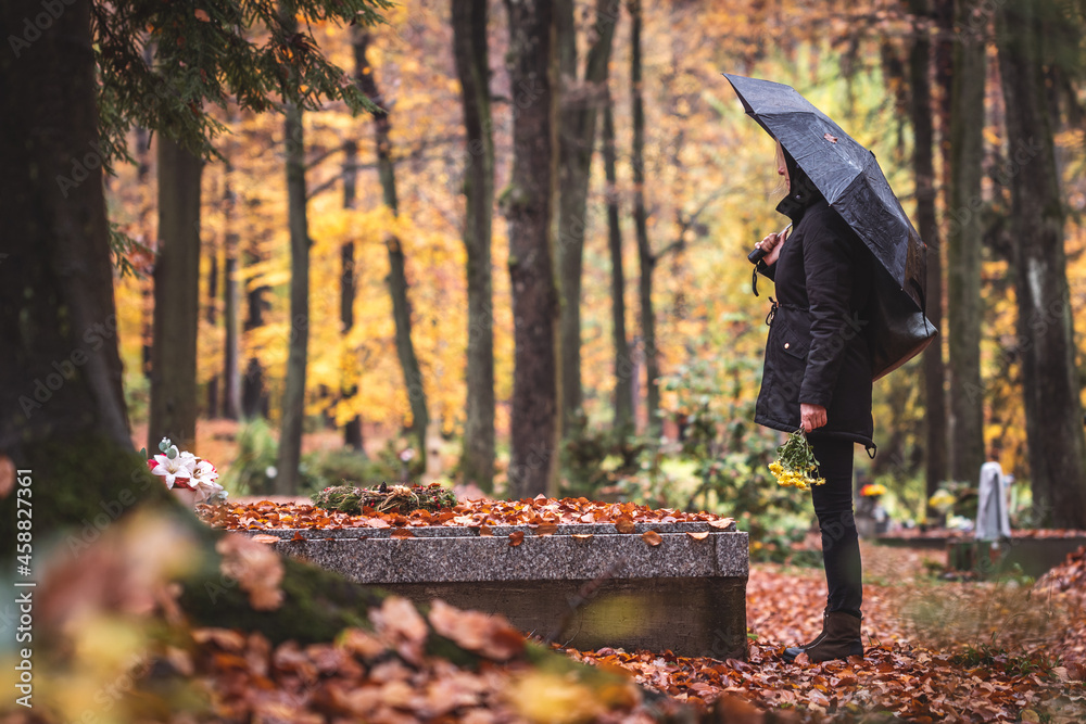 Silent grief in graveyard. Lone sad woman mourning for dead person at ...