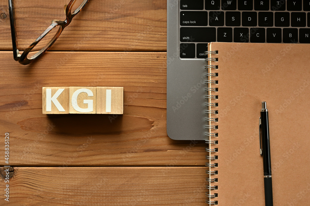 On the table there is a word cube lined KGI with laptop computers and ...