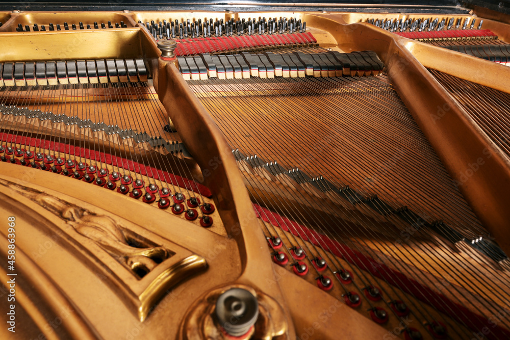 Inside an older grand piano with golden painted metal frame, strings ...