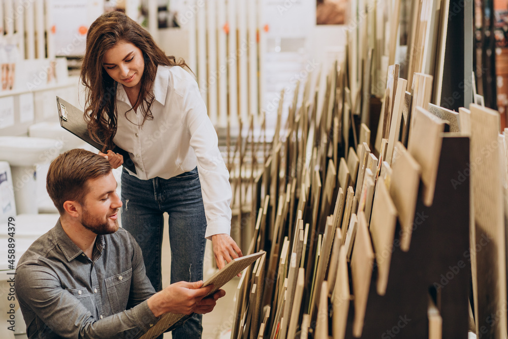 Young man with sales woman choosing tiles at building market Stock ...