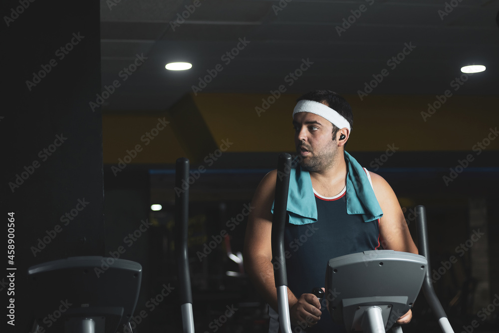 a funny fat boy doing sports inside a gym. overcoming concept ...