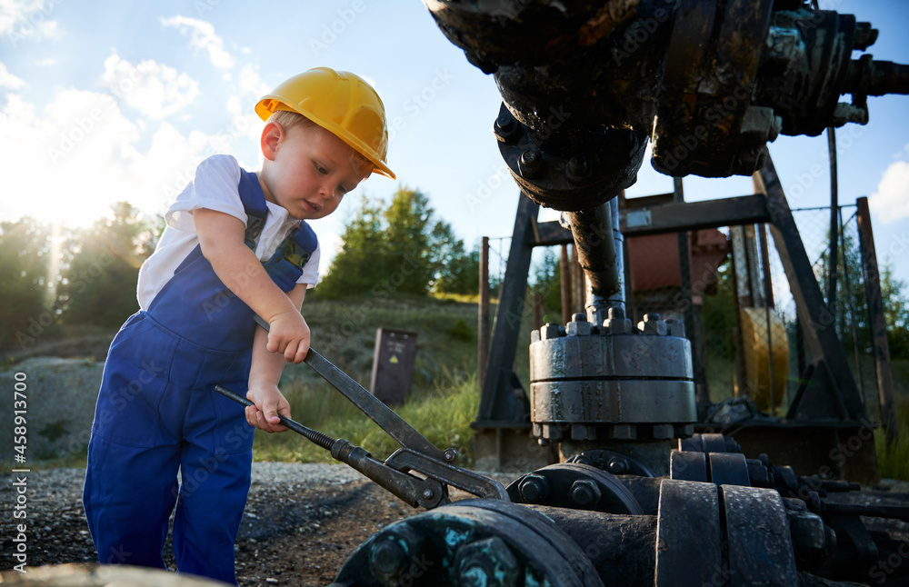 Caucasian blonde boy with instrument fixing drilling rig during time ...