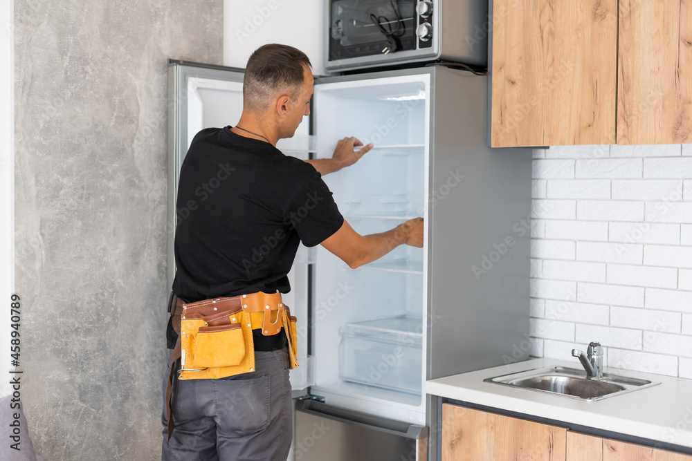 Young male worker repairing refrigerator Stock Photo | Adobe Stock