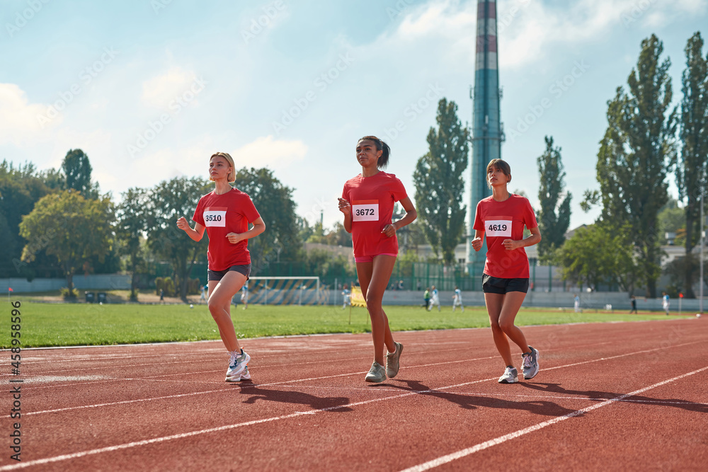 Full length shot of athletic young women running together during ...