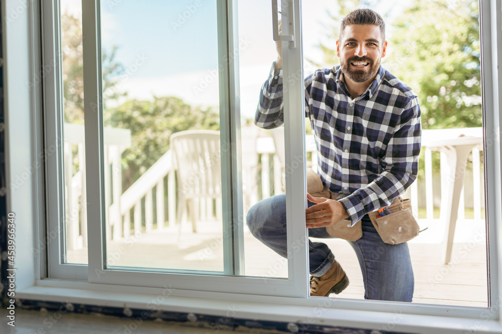 handsome young man installing bay window in a new house construction ...