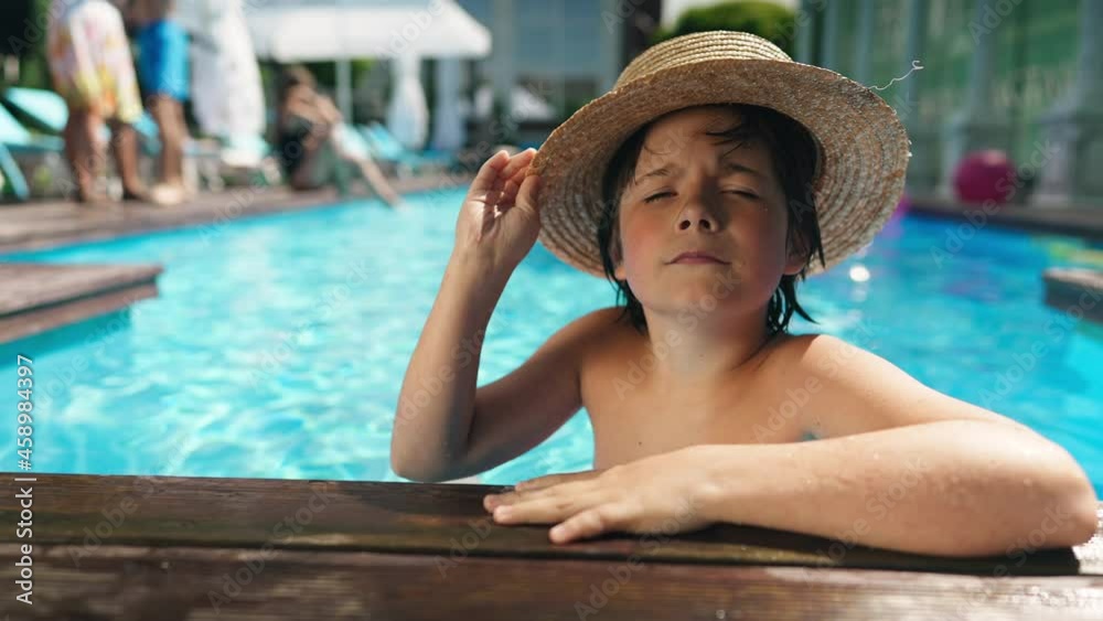 Cute confident little boy putting on straw hat smiling looking at ...