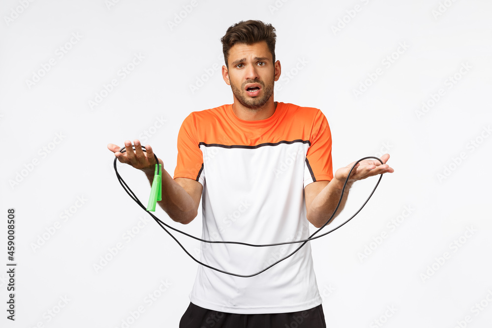 Gloomy handsome young guy dont know how use skipping rope, cant jump ...