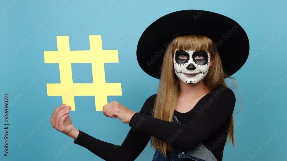 Portrait of girl child with Halloween mask holding big yellow hashtag ...