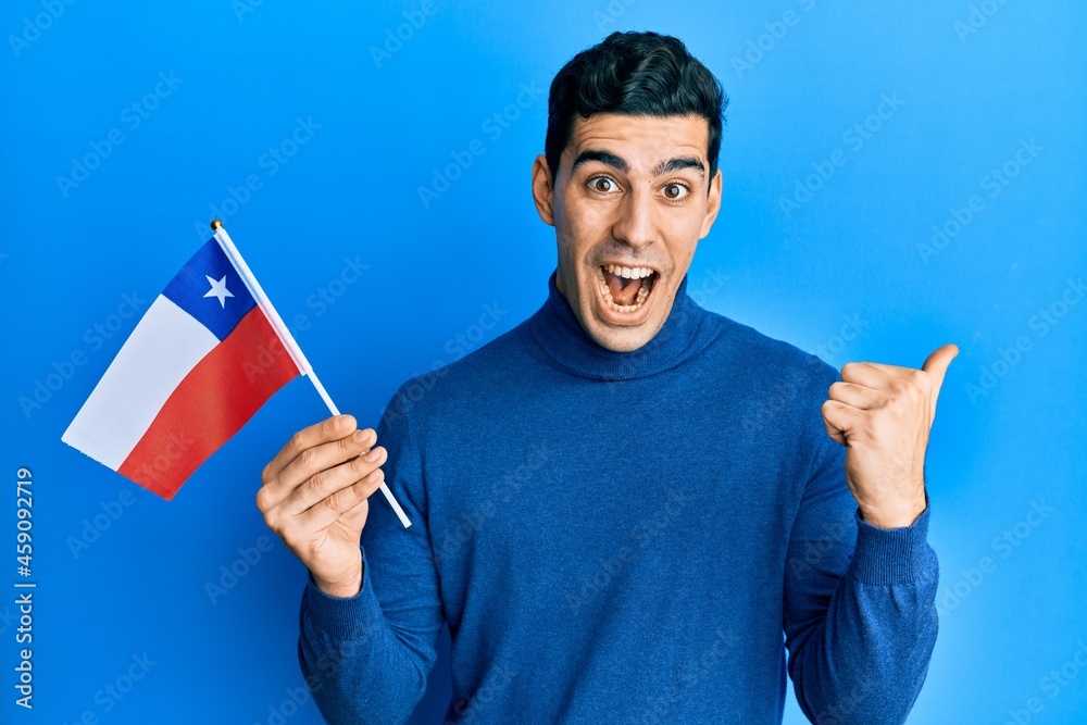 Handsome hispanic business man holding chile flag pointing thumb up to ...