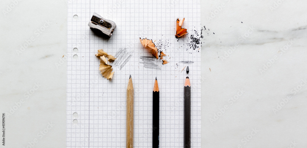 Simple black sketching pencil with a sharpener on quad paper sheet and ...
