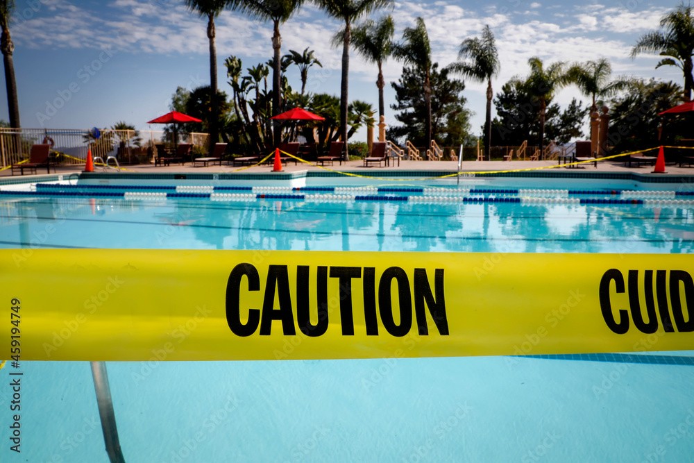 Yellow caution tape at a resort style pool preventing access or use of ...