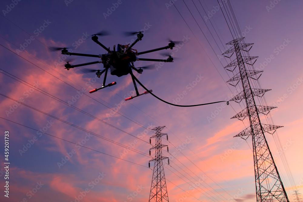 Silhouette of Drone stringing transmission lines of electrical high ...