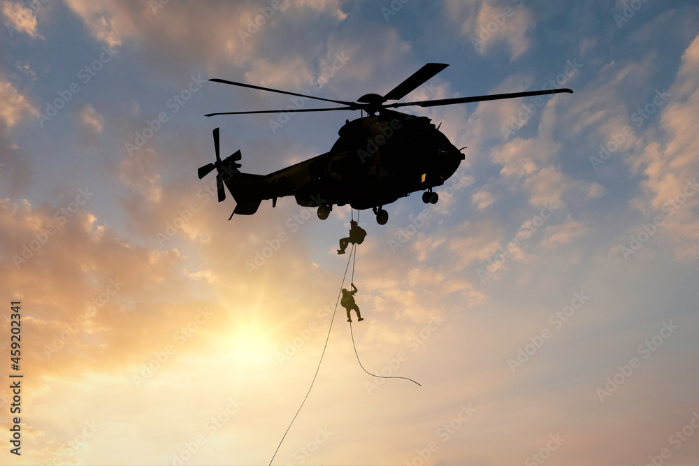 silhouette of military commando helicopter drops between are in flight ...