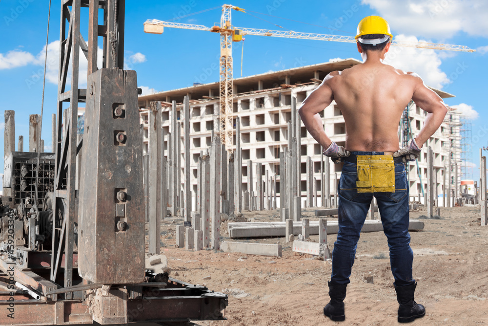 Brawny worker working at pile driver works to set precast concrete ...