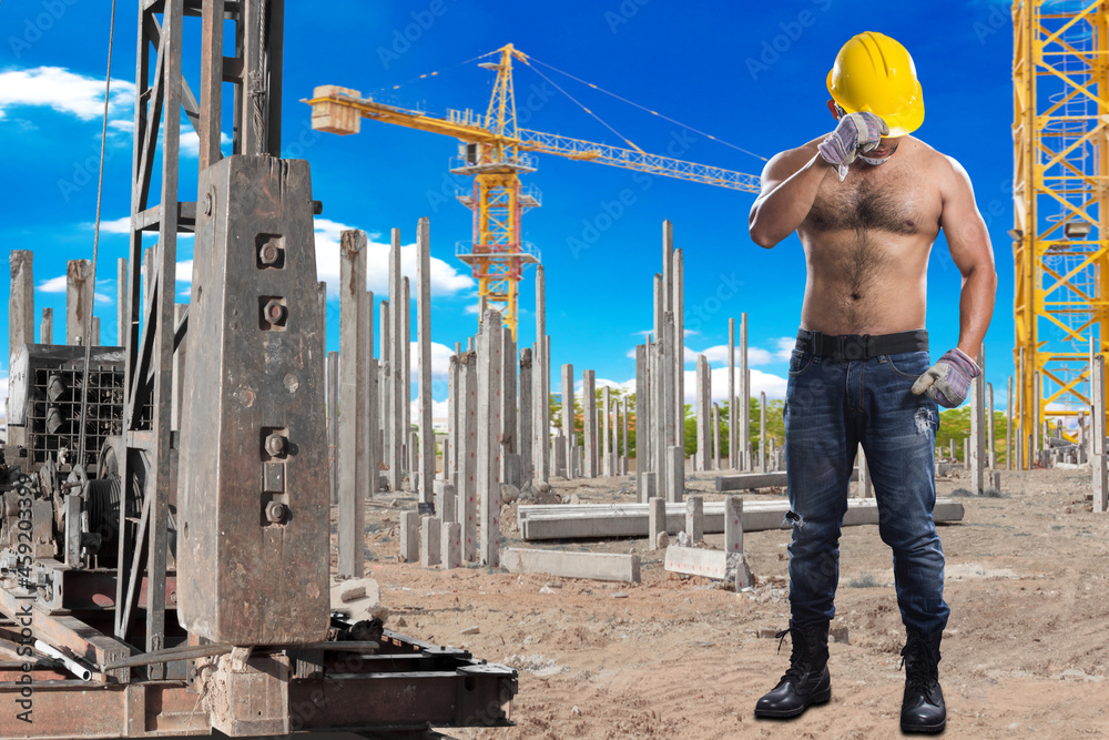Brawny worker at pile driver works to set precast concrete piles in a ...