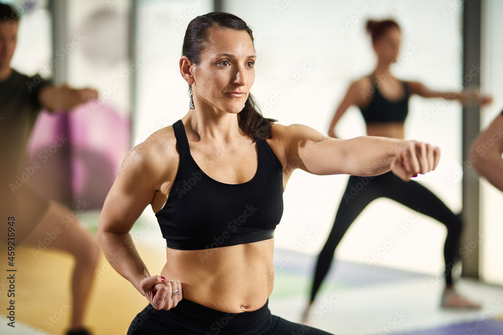 Athletic woman in fighting stance exercises hand punches during martial ...