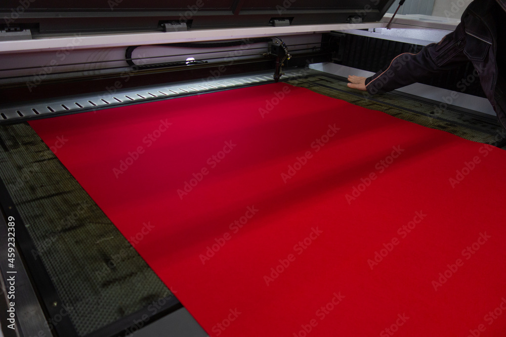 Felt fabric of red color, lying on the table of the laser machine ...