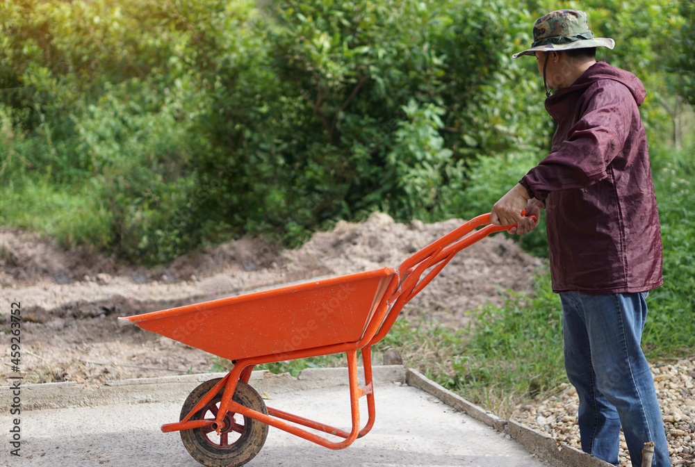 Asian man push orange wheel barrow cart trolley that use for ...