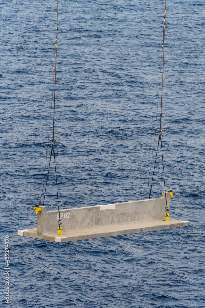 A concrete sleeper being lifted from a construction work barge for ...