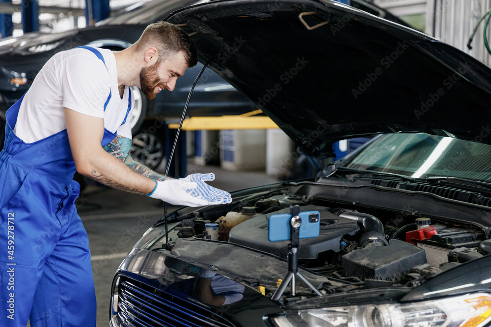 Young happy technician car mechanic man in blue overalls white t-shirt ...