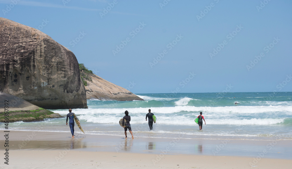 Group of surfers entering the sea, on the beach located at Posto 12 ...