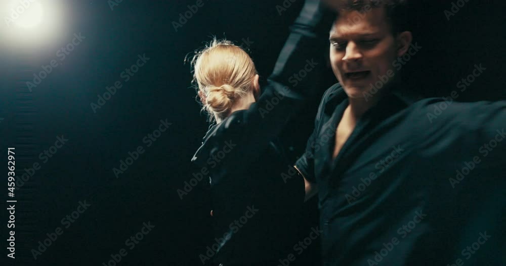 Dancers in black shirts dance in dark studio practice choreography ...