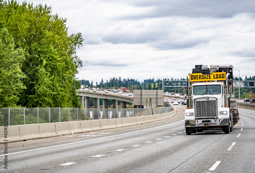 Powerful white big rig classic semi truck with oversize load sign on ...