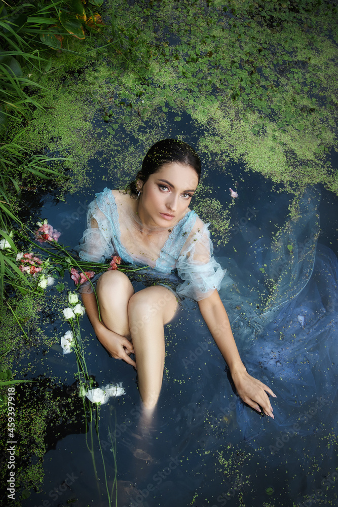 Art beautiful romantic woman lies in swamp in blue long dress with ...