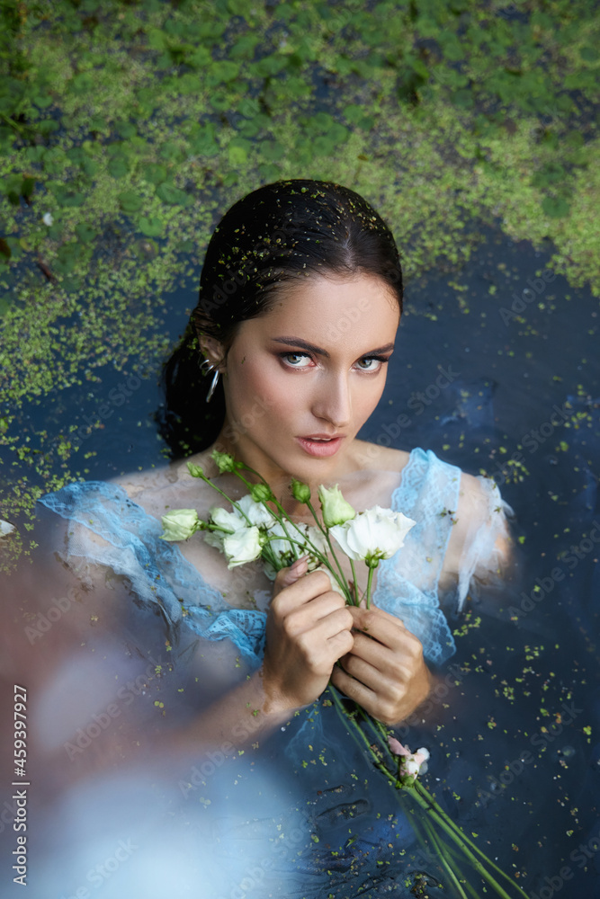 Art beautiful romantic woman lies in swamp in blue long dress with ...