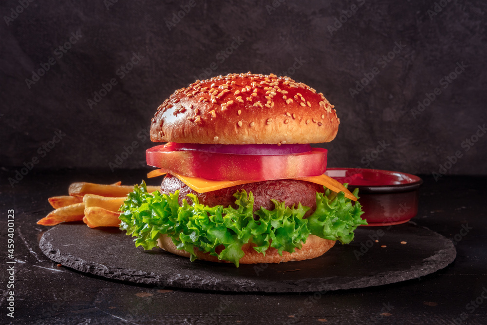 Burger side view on black, with French fries and ketchup. Fat beef ...