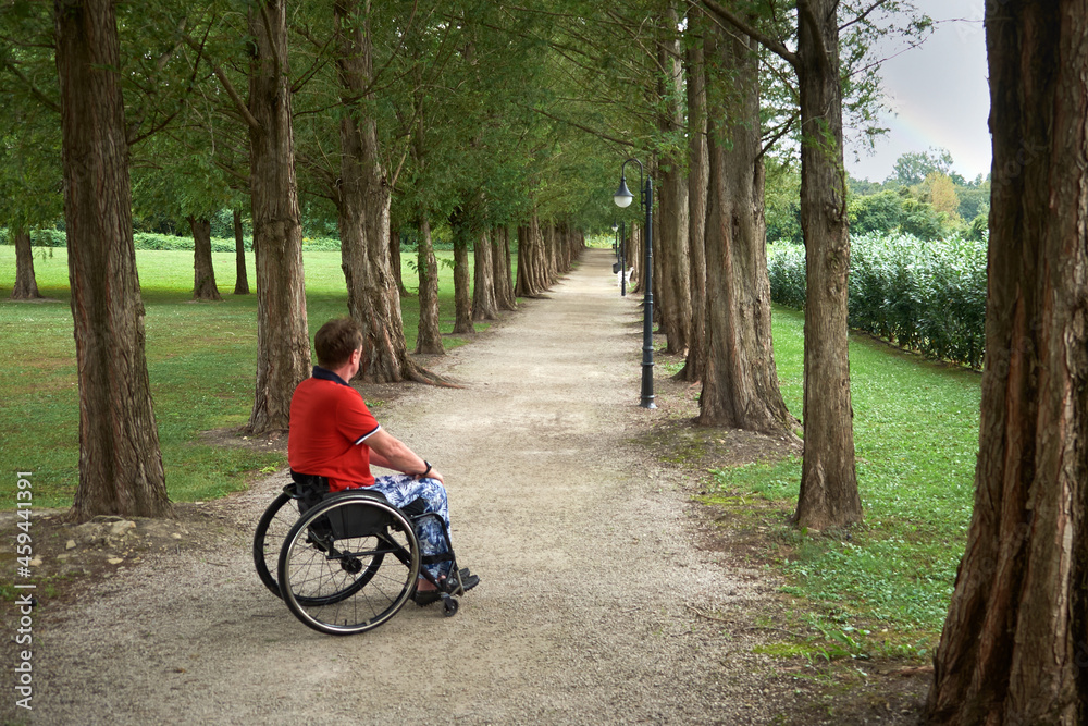 man in red polo shirt sits on the wheelchair and looks into the ...